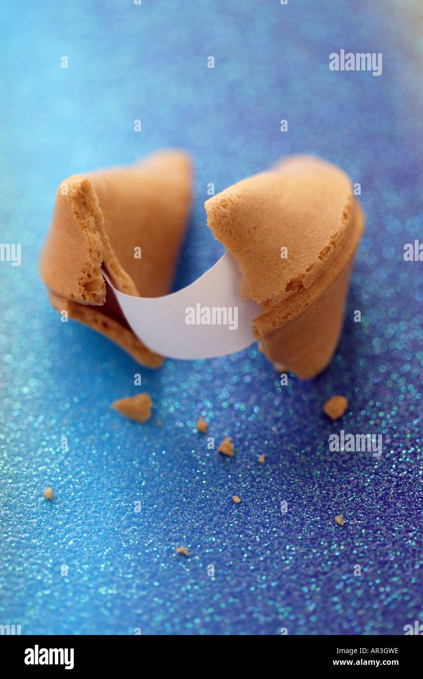 Broken fortune cookie revealing message on blue metallic background ...