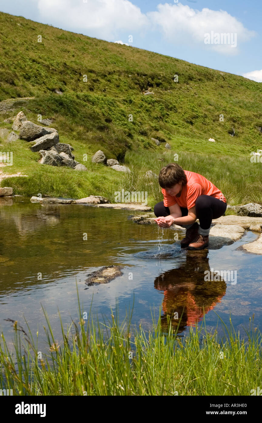 Female walker, drinking water from stream Stock Photo - Alamy