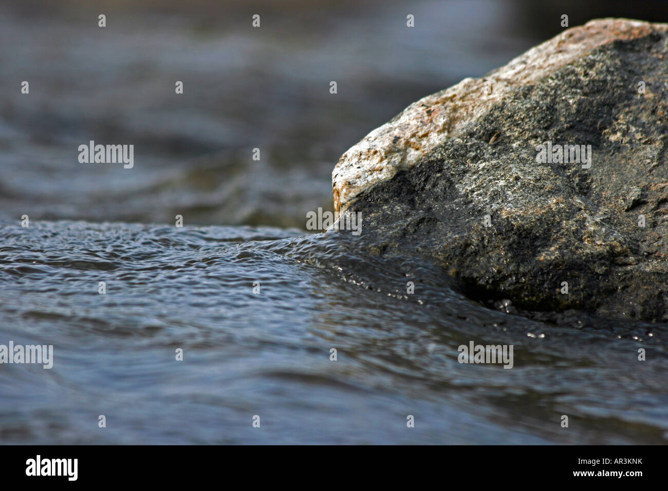 Current of water in a river flowing around a rock Stock Photo - Alamy