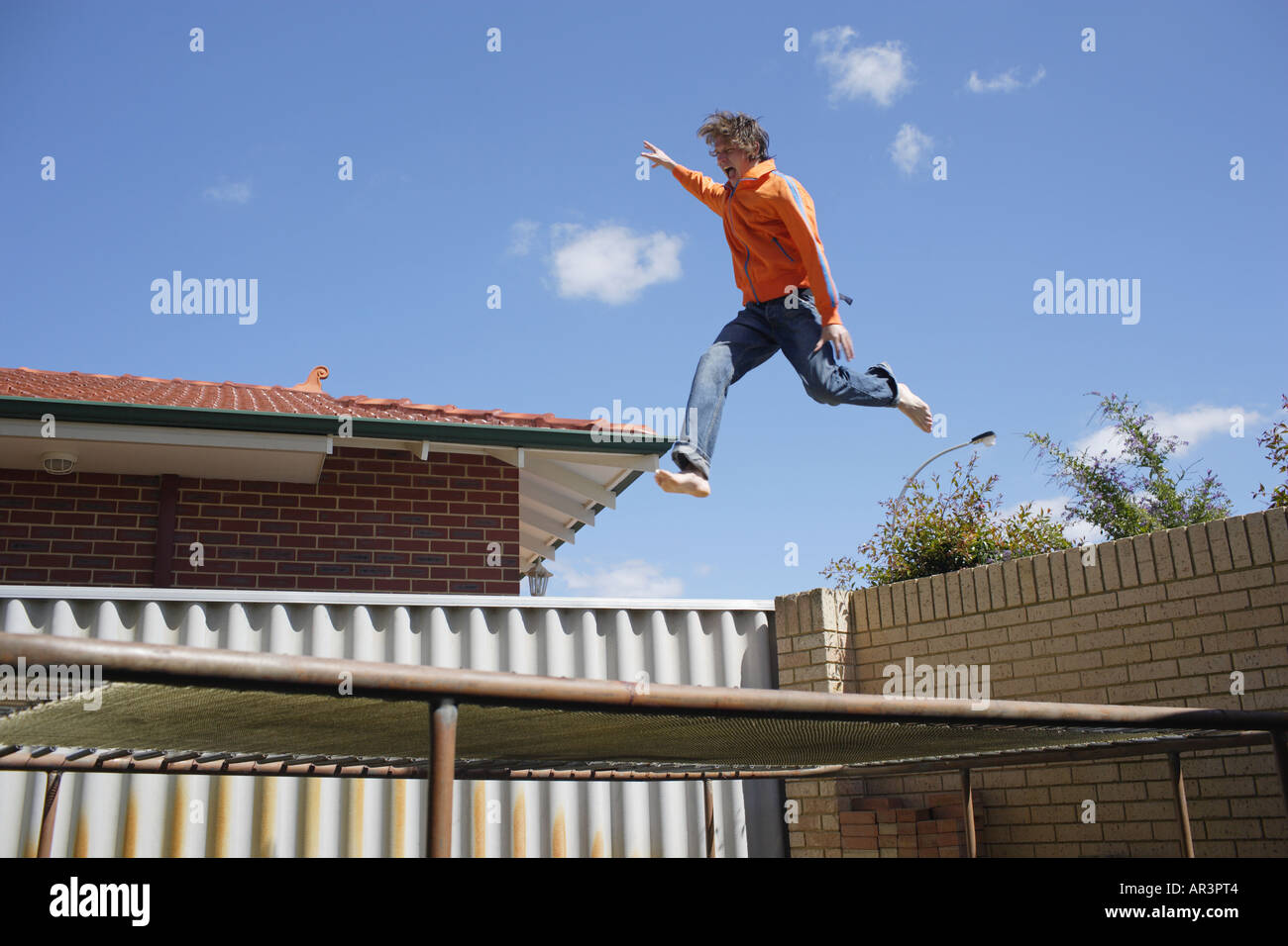 Young man jumping on trampoline Stock Photo - Alamy