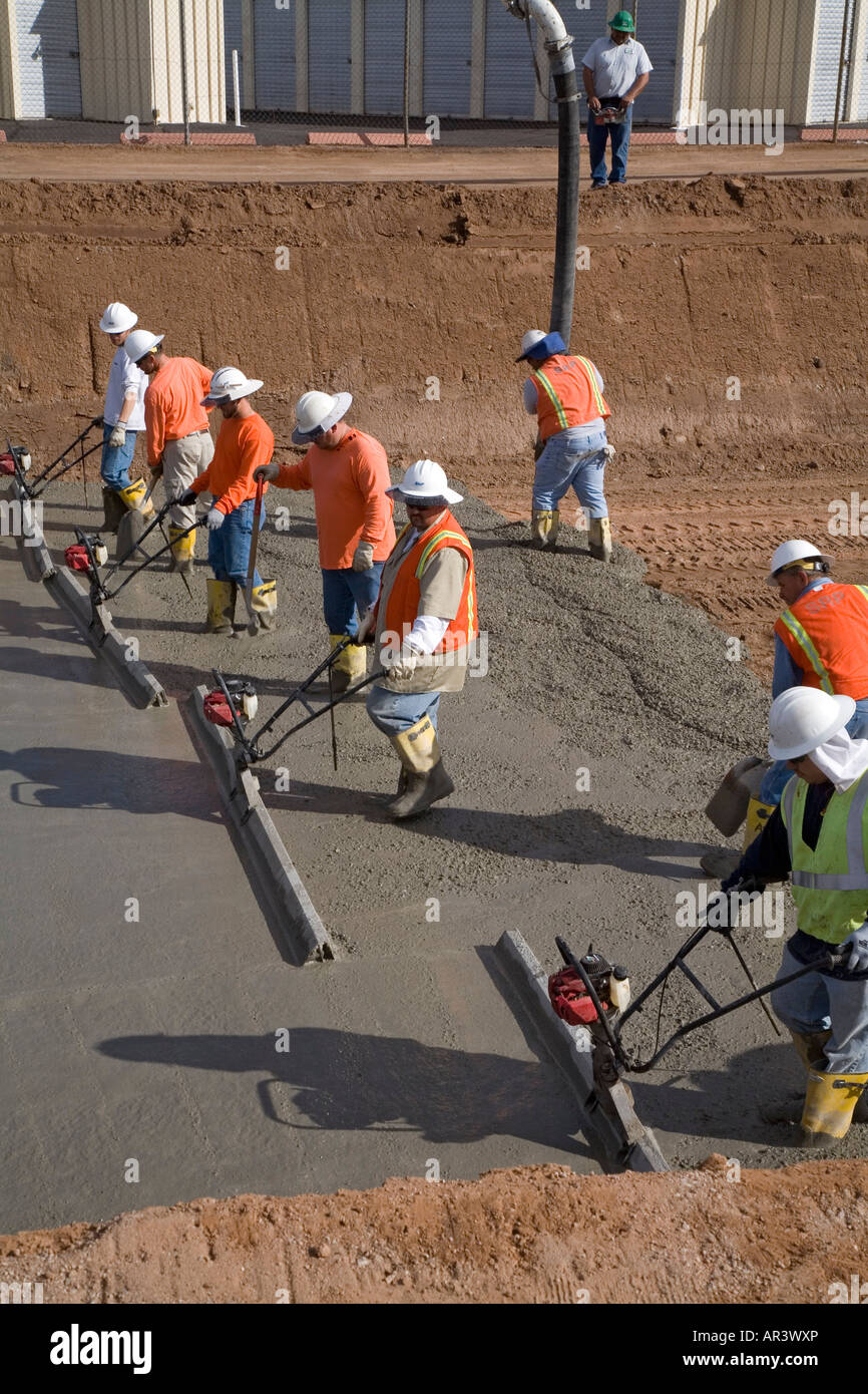 Workers line water supply canal with concrete to diminish water loss ...
