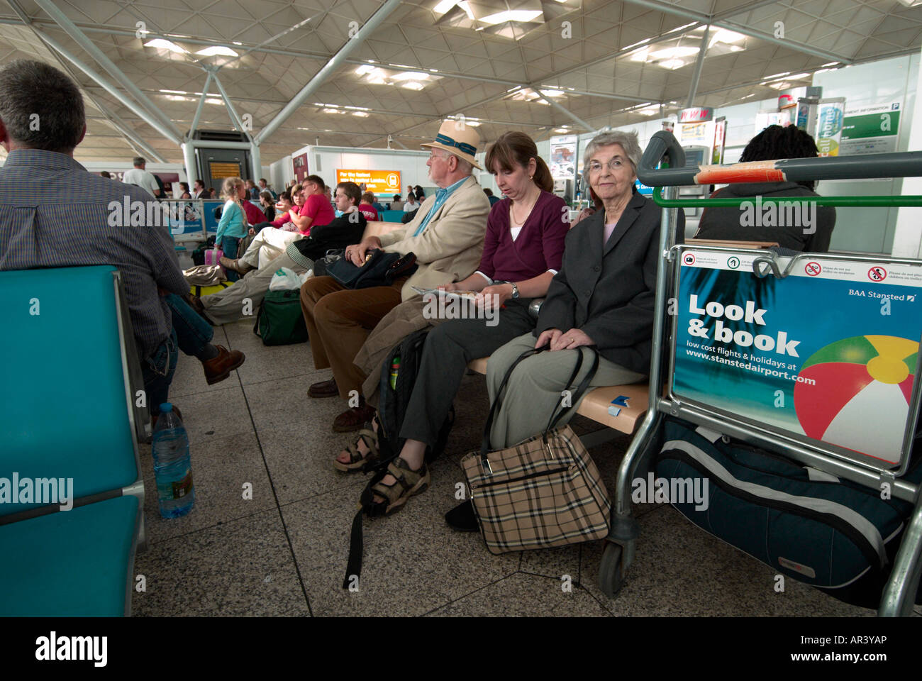Passengers inside Stansted Airport sitting waiting with light hand ...