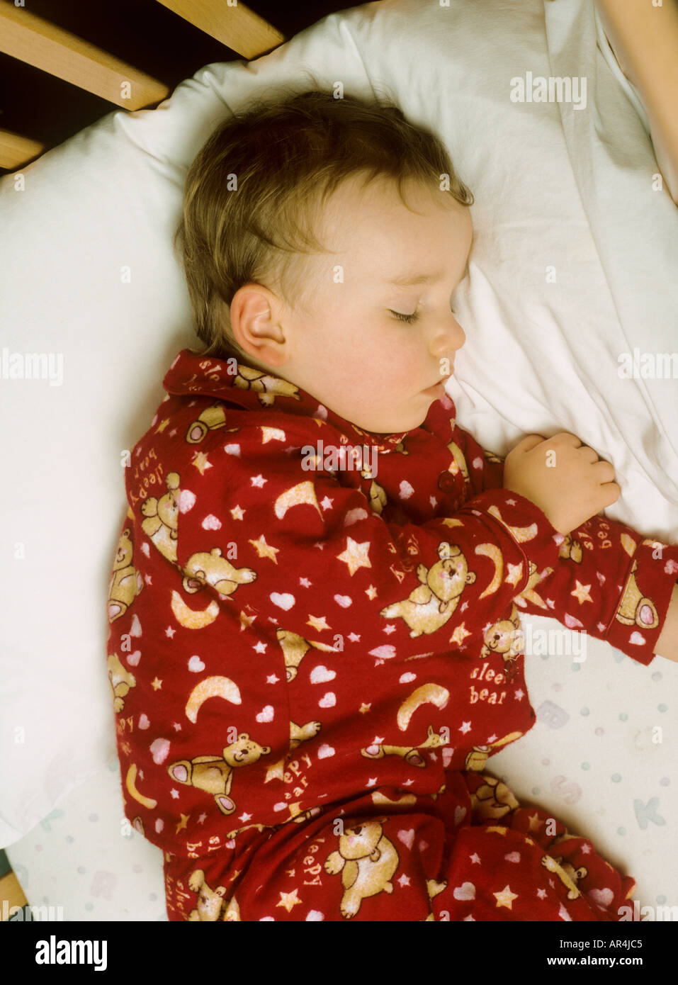 Young boy wearing pyjamas sleeping in cot Stock Photo - Alamy