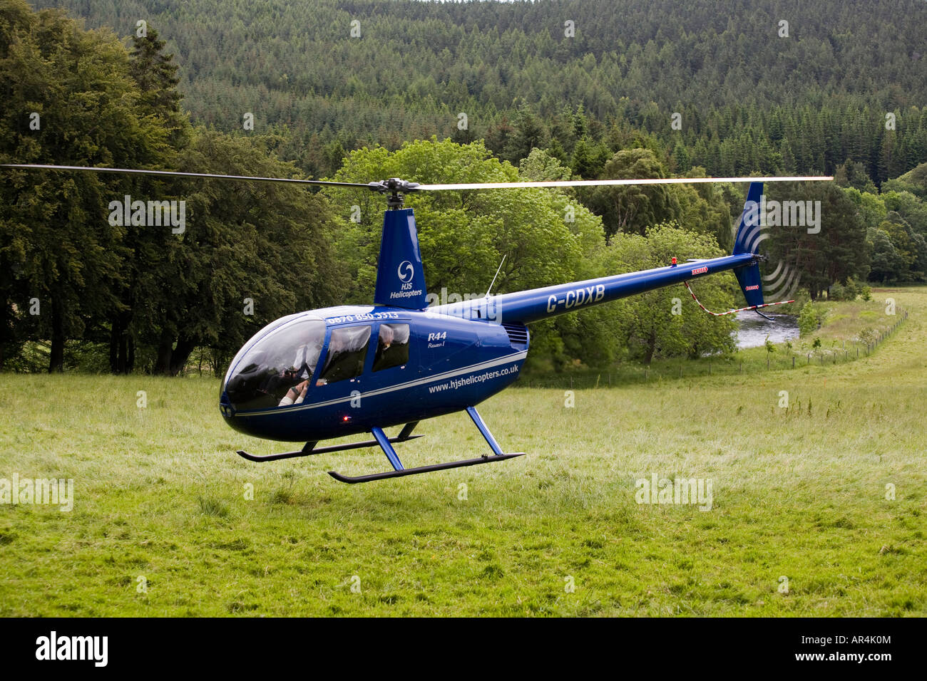 Robinson R44 four-seat light helicopter in flight hovering and about to ...