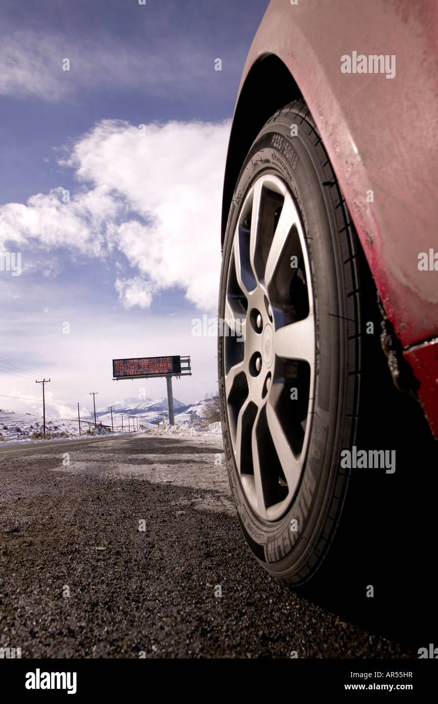 Winter driving front wheel of car with snow warning sign in thedistance ...