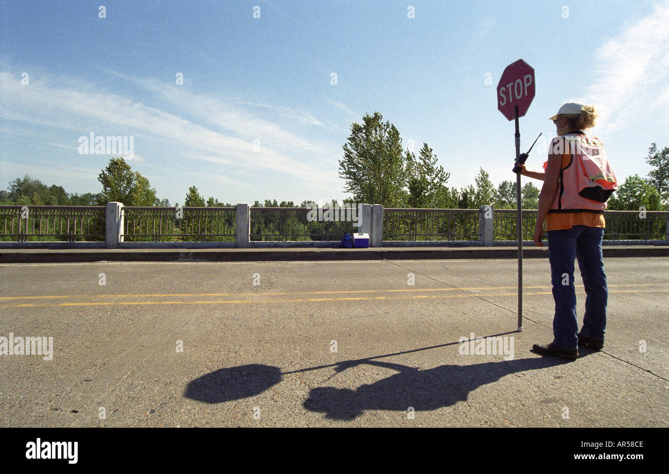 Female road worker holding up stop sign Stock Photo - Alamy