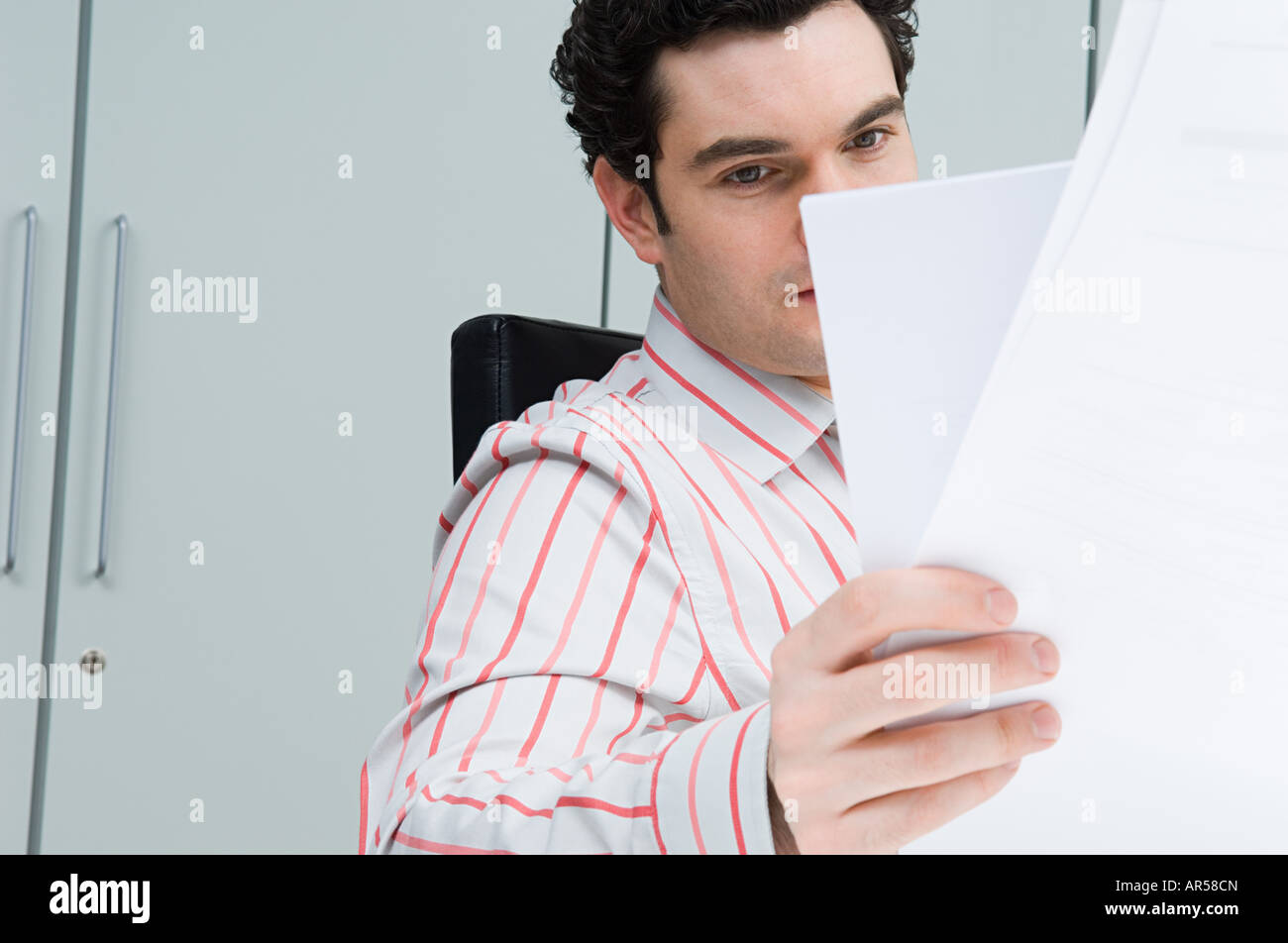 Man reading paperwork Stock Photo - Alamy
