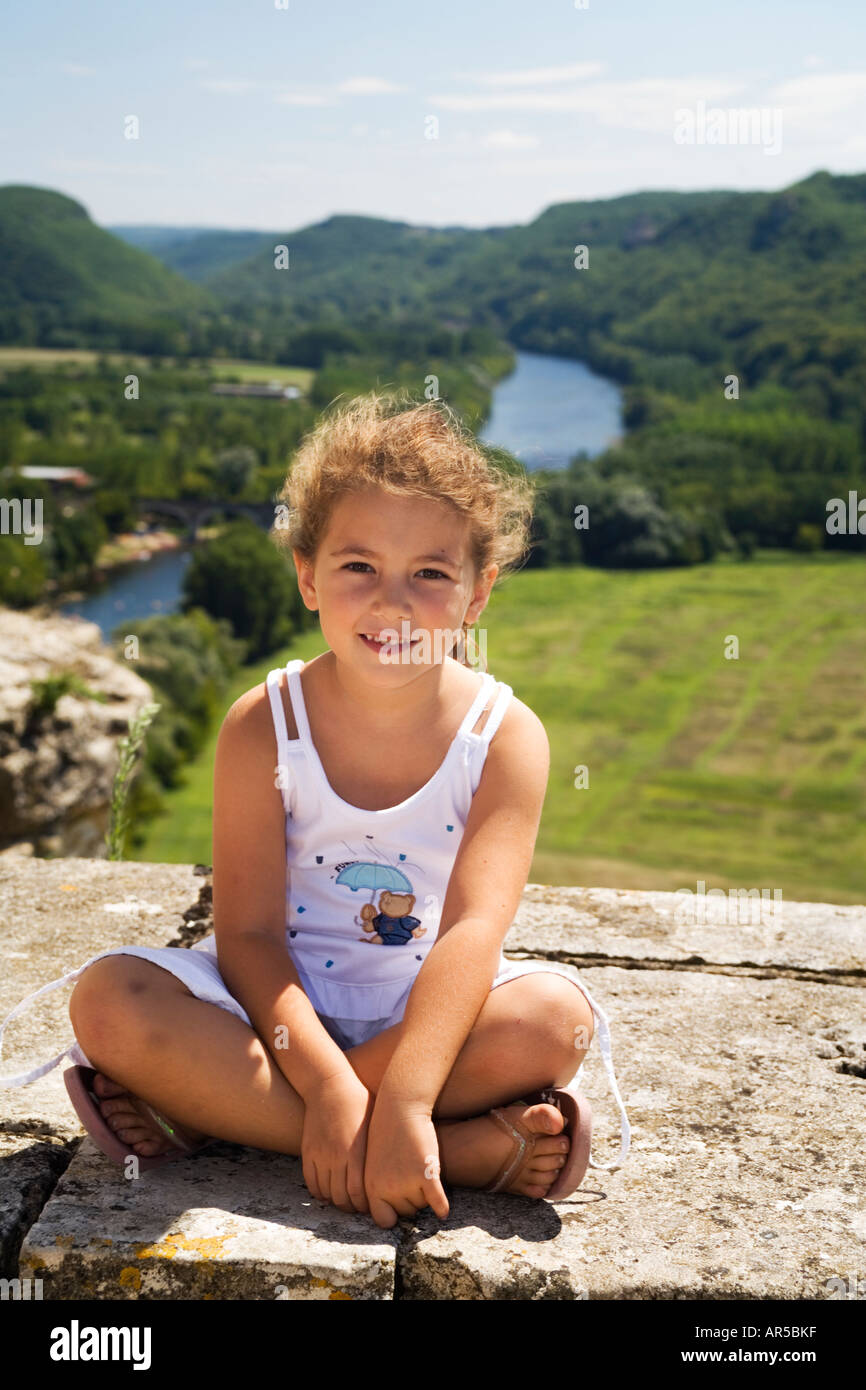Pretty child sitting with crossed legs with beautiful French landscape ...