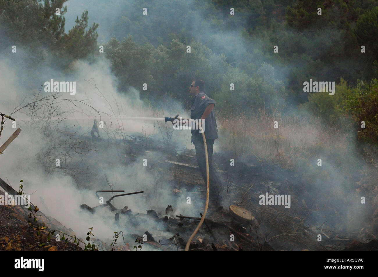 Fireman as seen through thick smoke putting out fire during massive ...