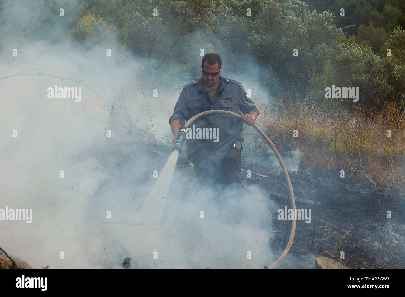 Fireman as seen through thick smoke putting out fire during massive ...