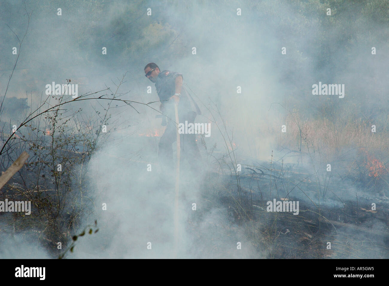 Fireman as seen through thick smoke puting out fire during massive ...