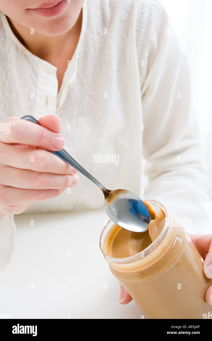 Woman scooping peanut butter from jar Stock Photo - Alamy