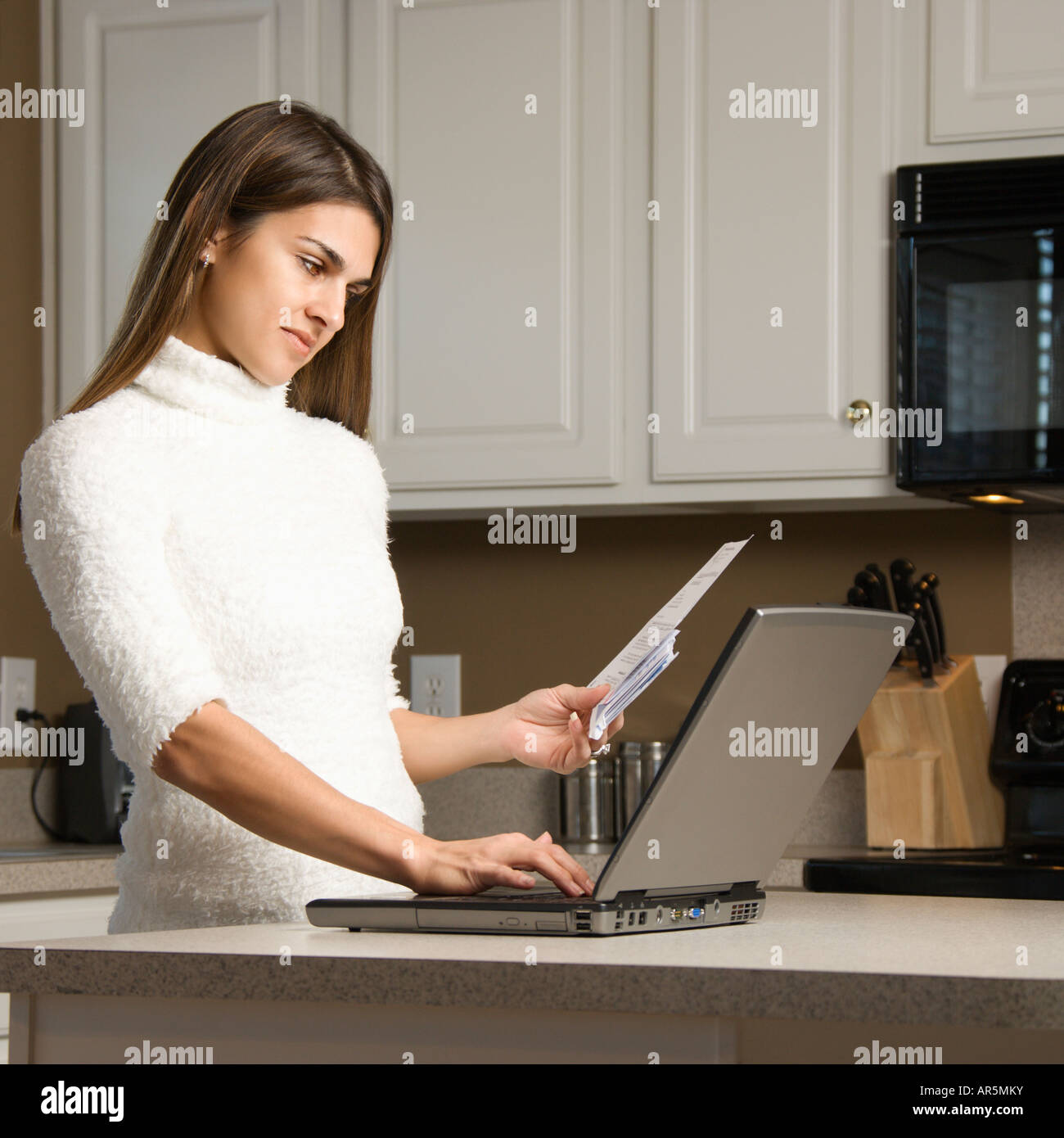 Caucasian woman in kitchen looking at laptop computer Stock Photo - Alamy