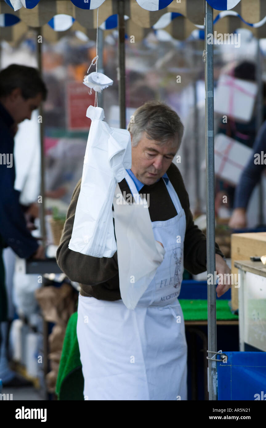 Stallholder wearing a white apron at marketmarket Stock Photo - Alamy