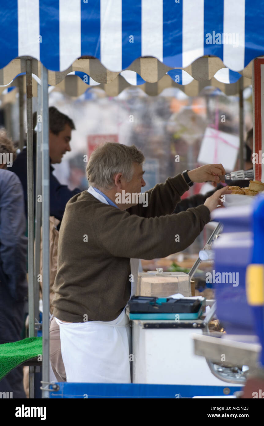 Stallholder behind the counter at food market Stock Photo - Alamy