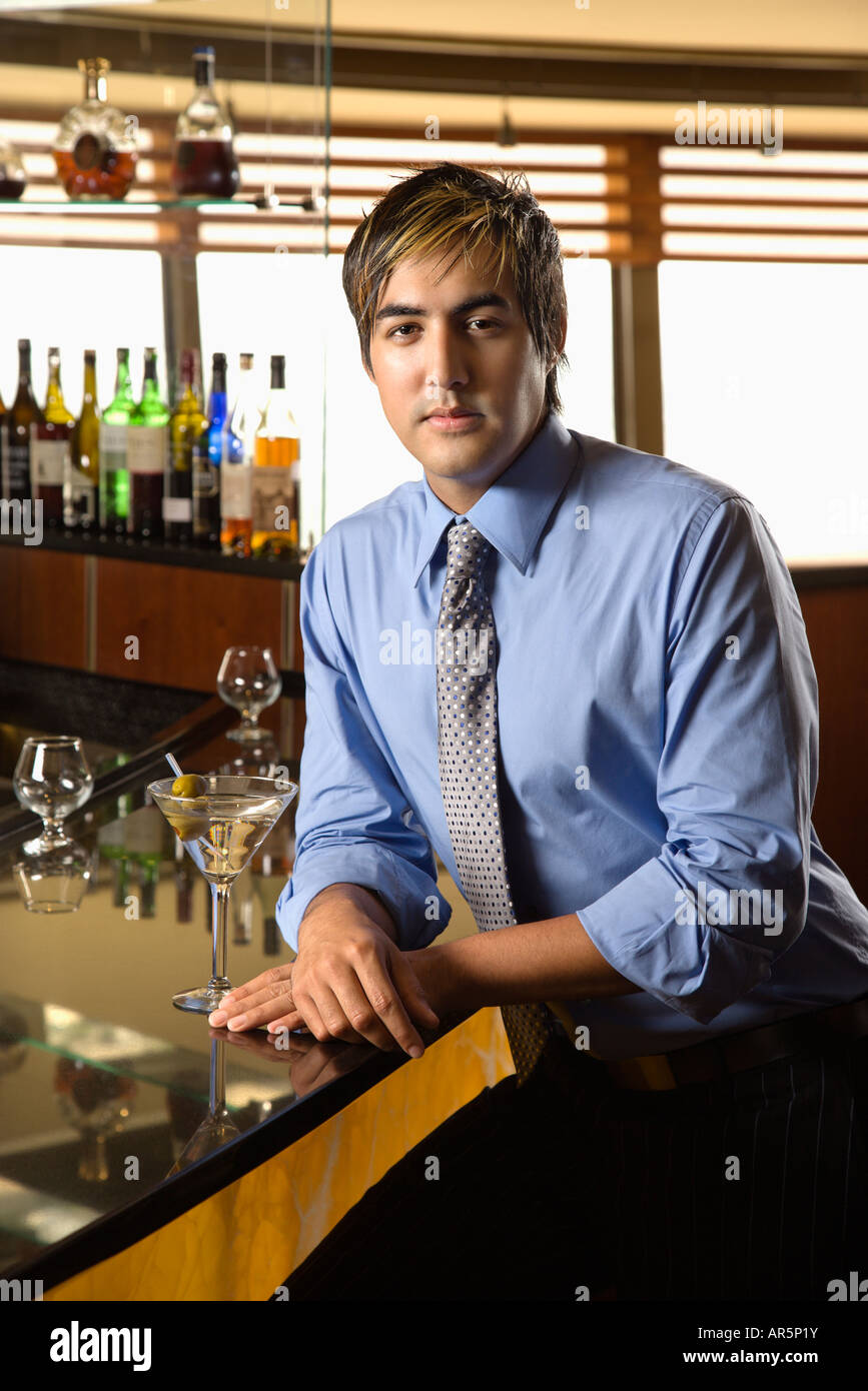 Hispanic mid adult man leaning on bar with martini looking at viewer ...