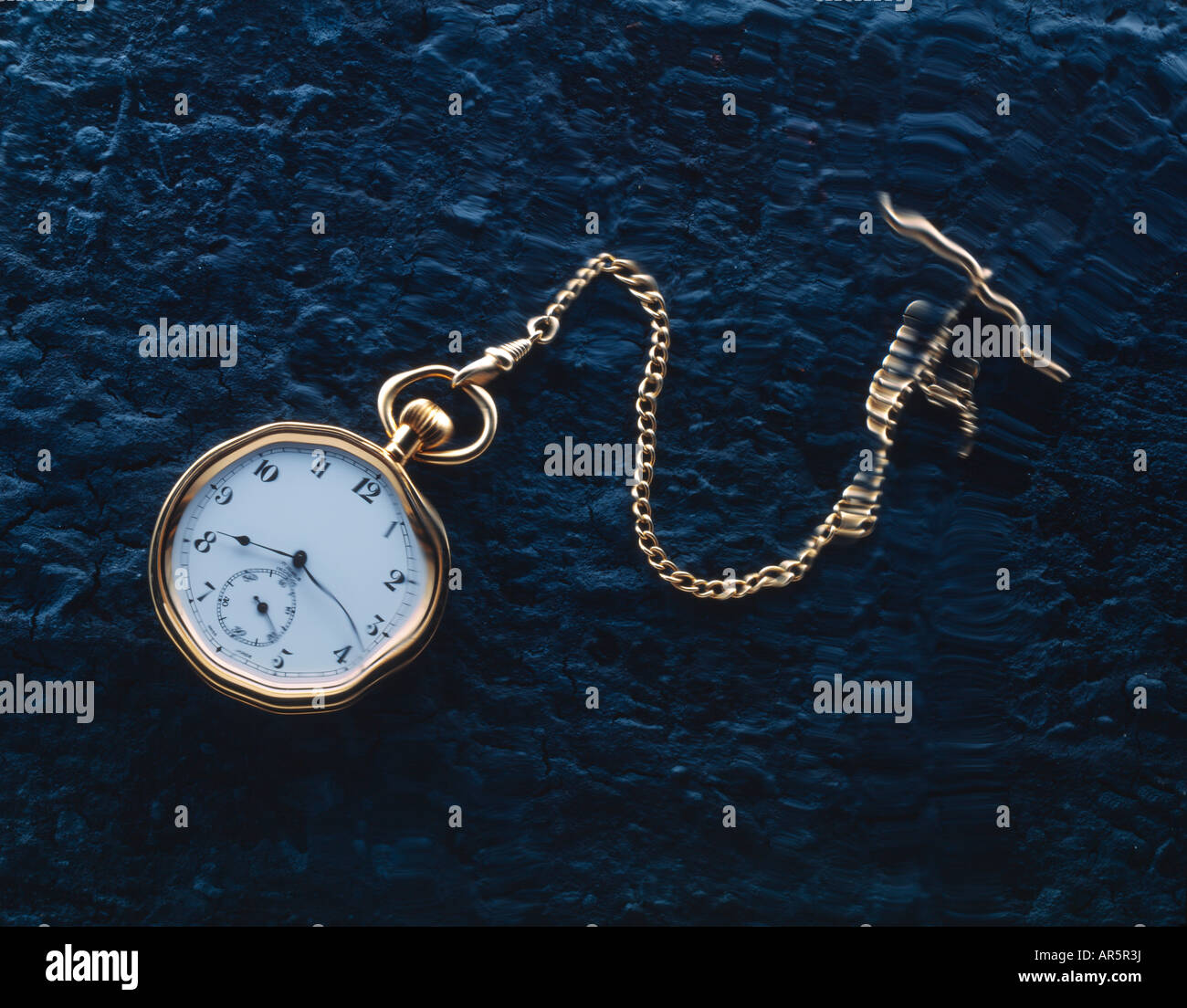 An old fashioned pocket watch on a chain bent by ripples Stock Photo ...