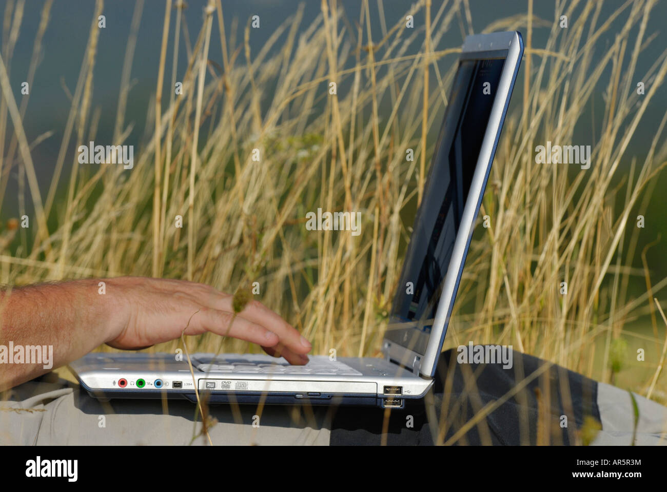 MAN WORKING AND LEARNING IN FRONT OF A LAPTOP COMPUTER ON THE GRASS ...