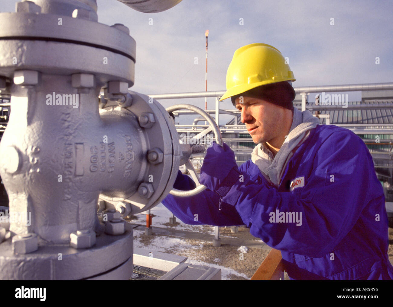 Oil industry worker turning valve at refinery Stock Photo - Alamy