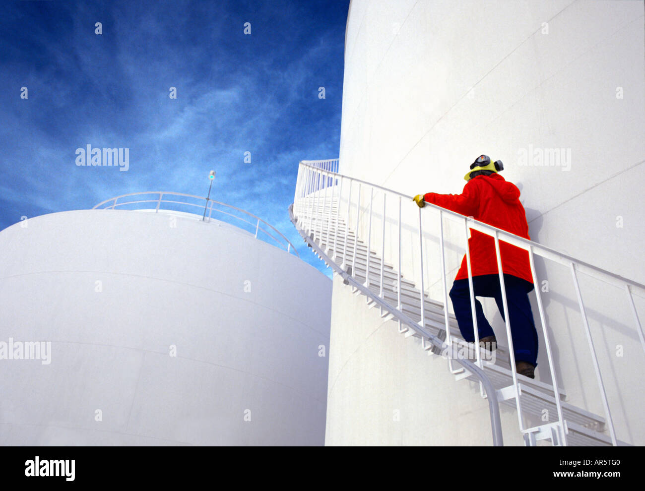 Oil industry worker climbing stairs on storage tank Stock Photo - Alamy