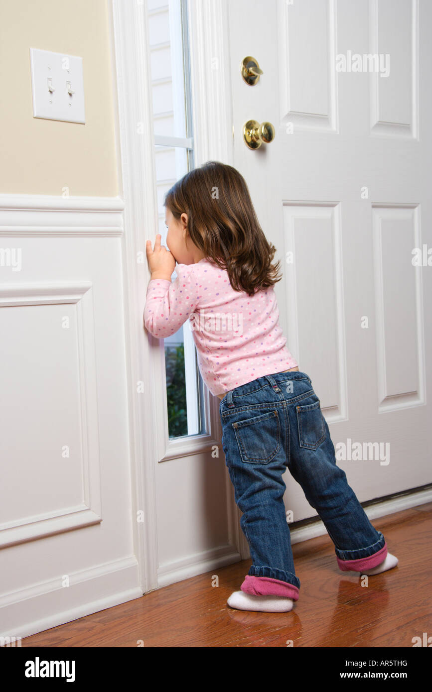Caucasian girl toddler peeking out of window by door Stock Photo - Alamy