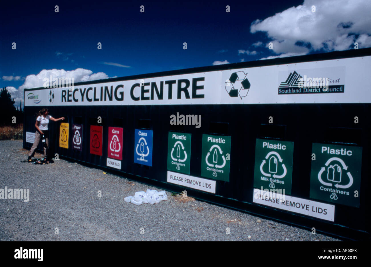 Person using a roadside recycling station (depository) showing signage ...