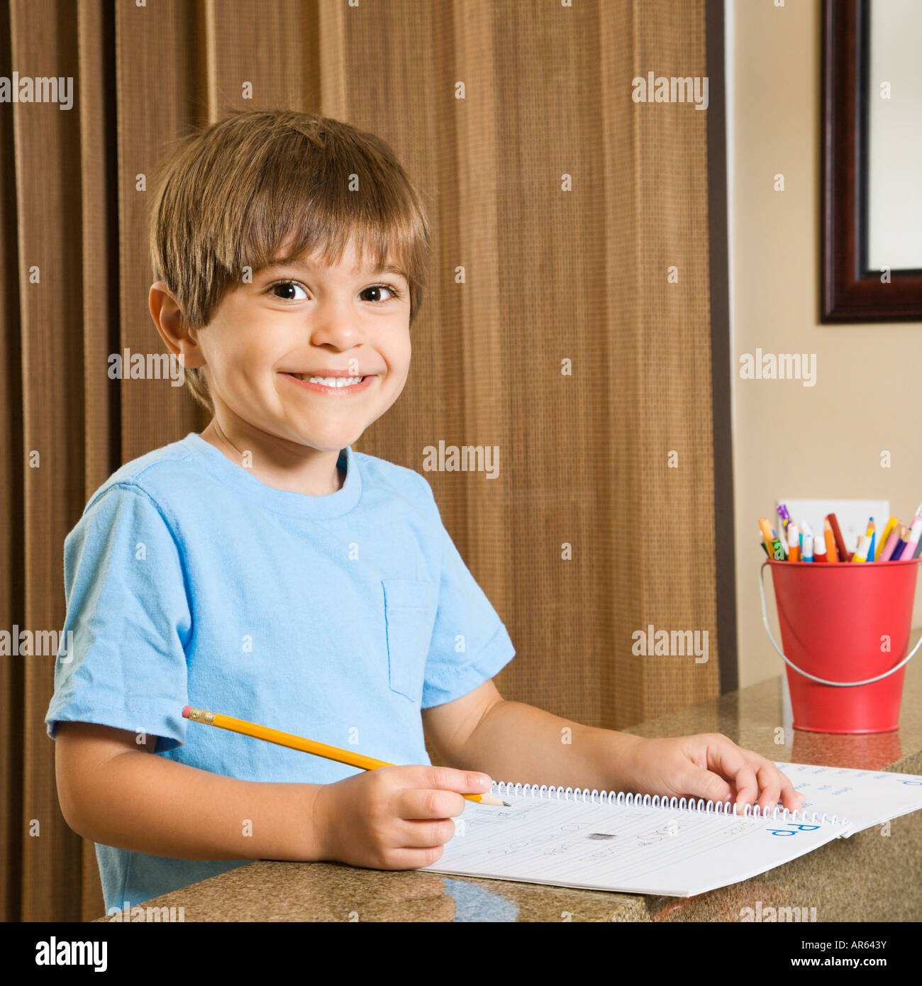 Hispanic boy smiling at viewer and doing homework Stock Photo - Alamy