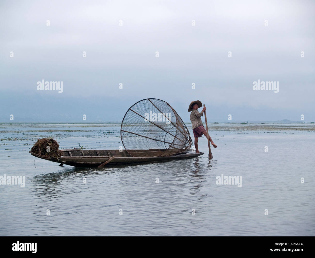 boy rowing with one leg on Inle Lake a traditional practice of Burmese ...