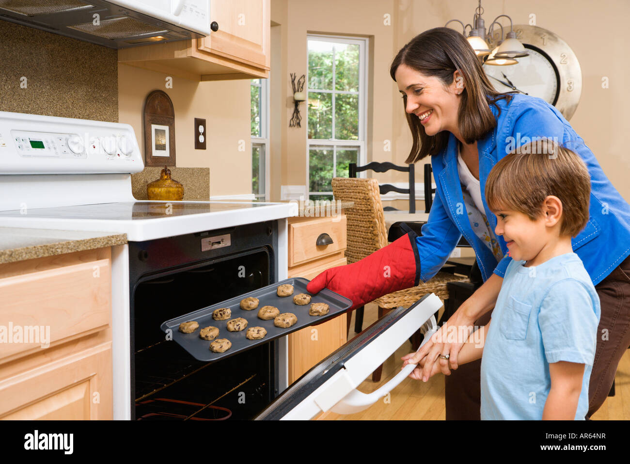 Side view of Hispanic mother and son putting cookies into oven Stock ...