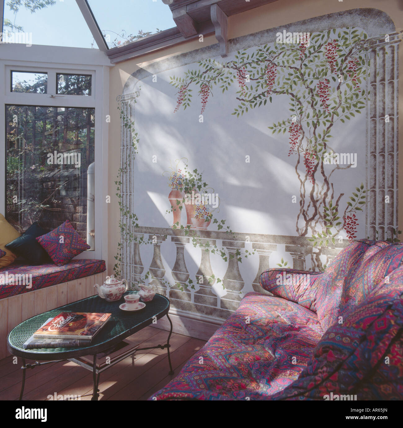 Painted mural on wall of conservatory living room with patterned sofa ...