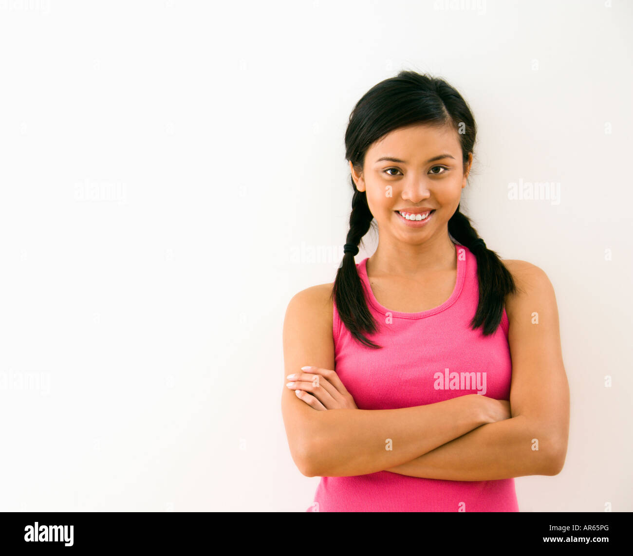 Portrait of young woman standing with arms crossed smiling Stock Photo ...