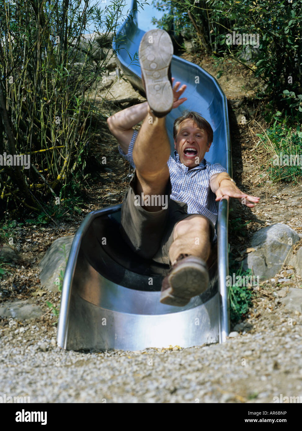Excited man comes down slide Stock Photo - Alamy