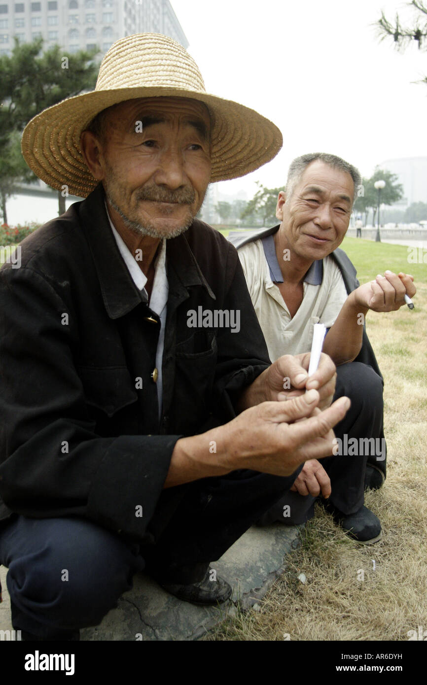 Two gardeners take a pause from work and enjoy a cigarette break in ...