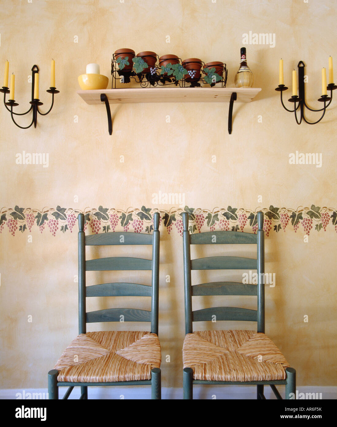 Rush seated green ladderback chairs below shelf on ragging paint effect ...