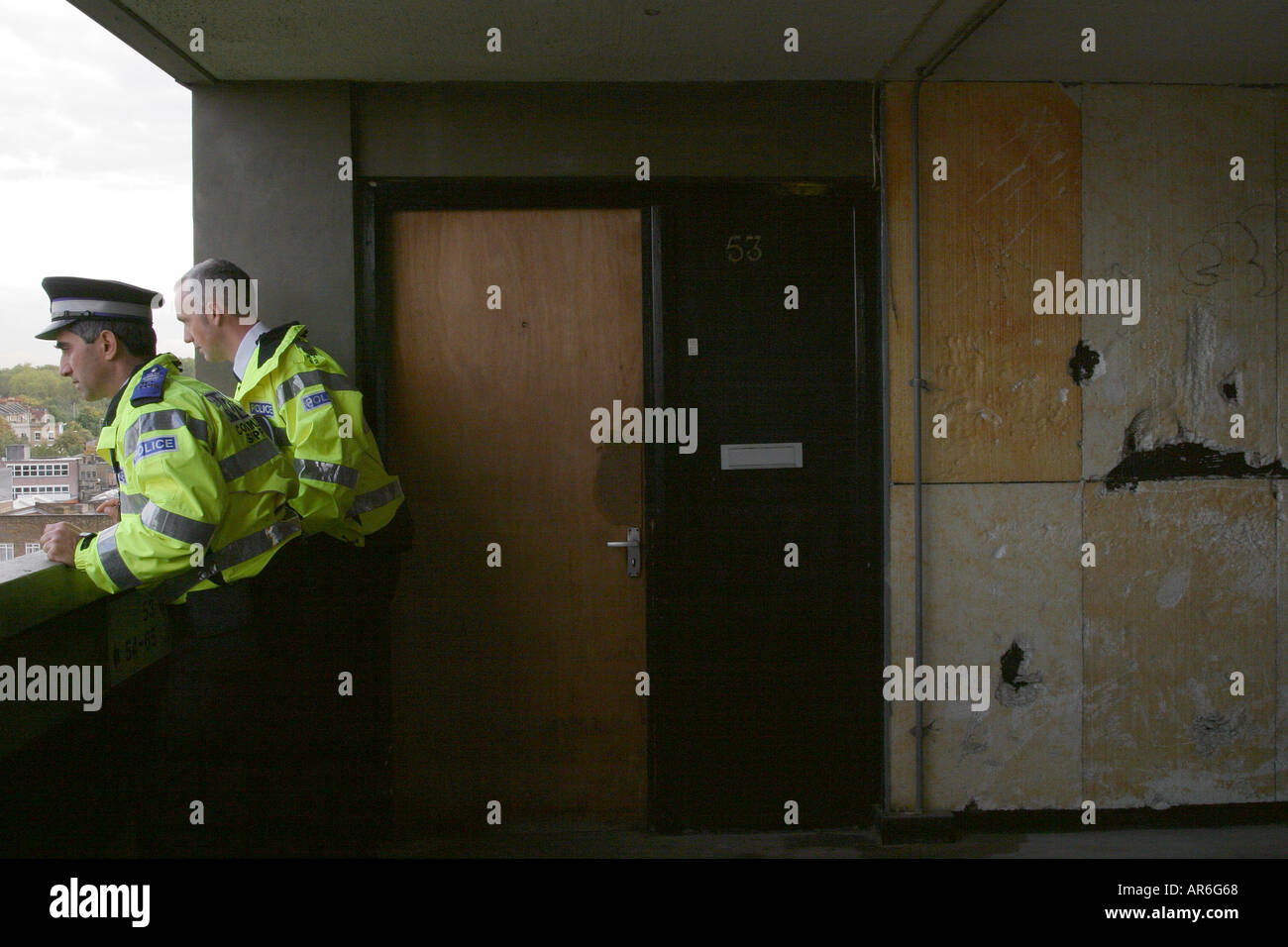 A Police Officer and a Community Support Officer look over a balcony ...