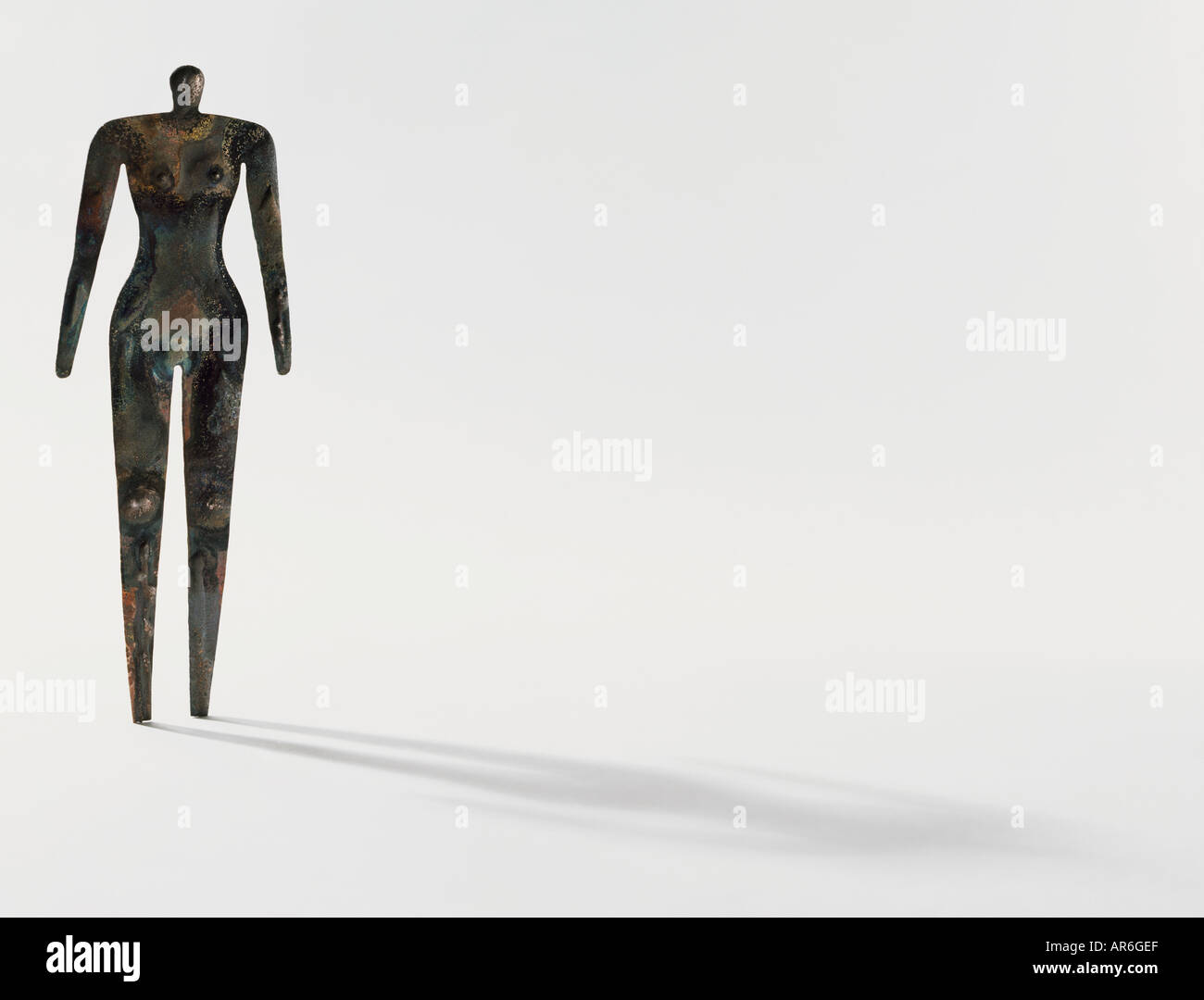 Metal sculpture of solitary human figure with elongated limbs and small ...