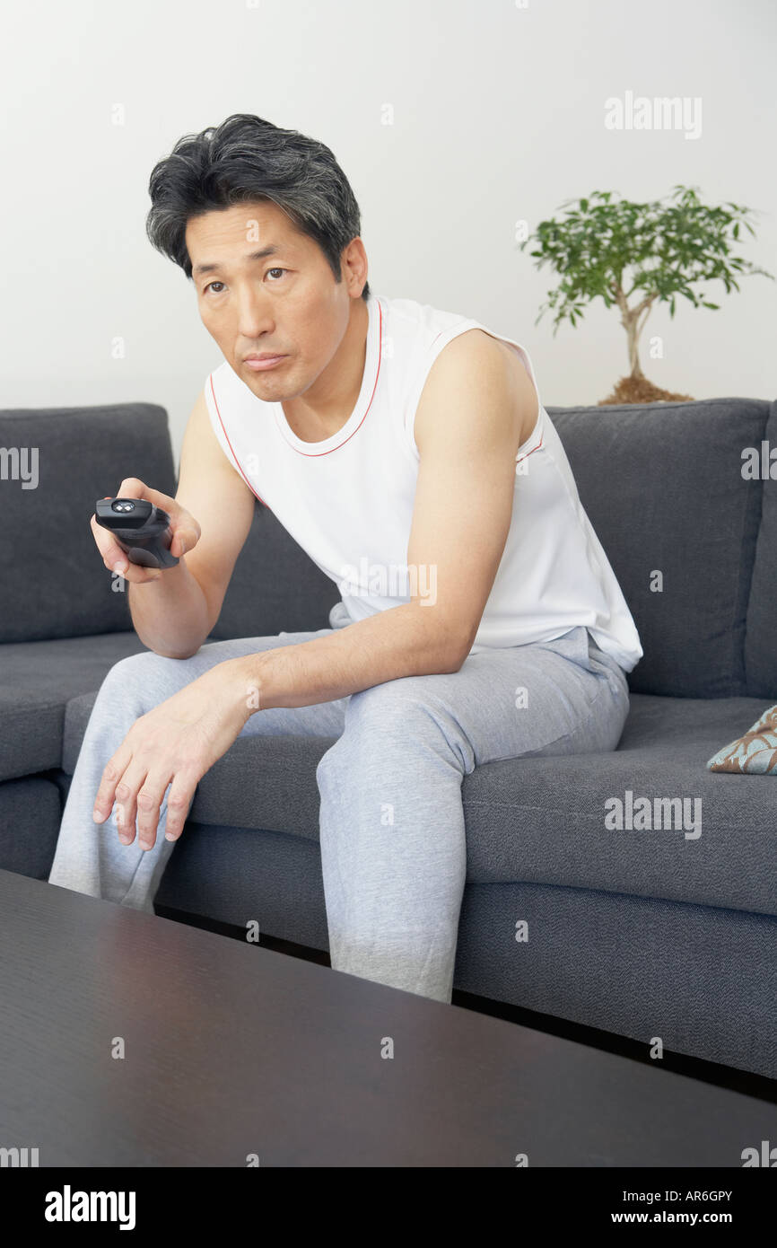 Asian man pointing remote control Stock Photo - Alamy