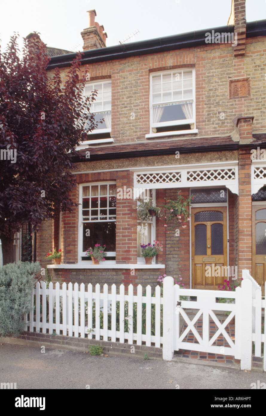 White gate and picket fence in front of Victorian terraced cottage with ...