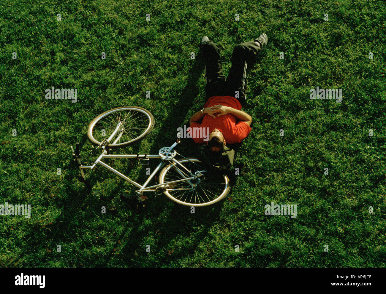 man sleeping on grass by bicycle Stock Photo - Alamy