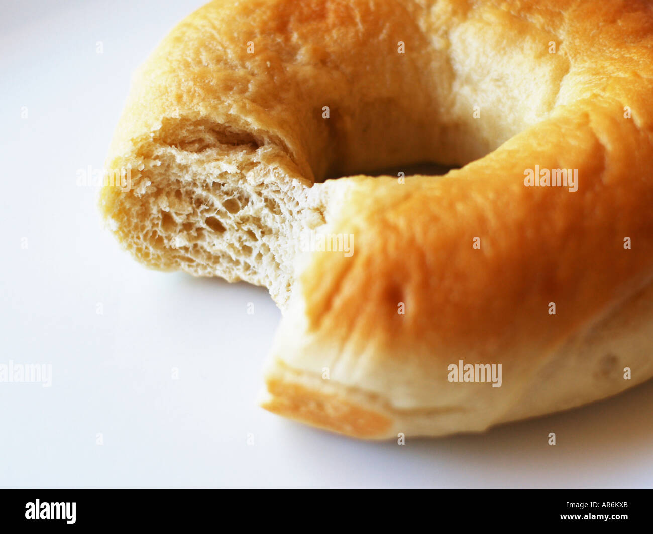 White flour (regular) bagel against white background with a bite taken ...