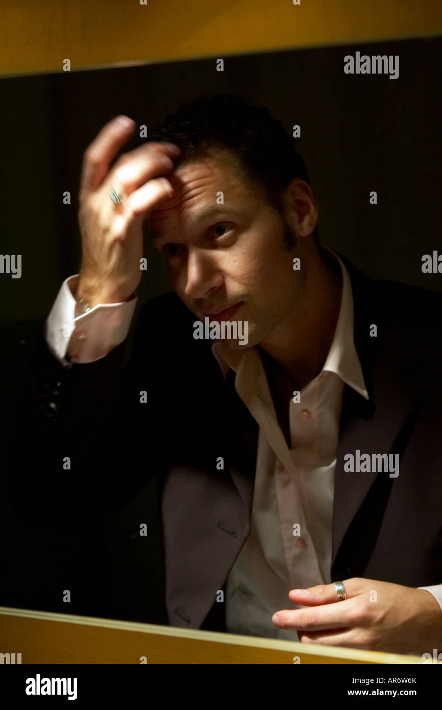 Young man looking at himself in a mirror Stock Photo - Alamy