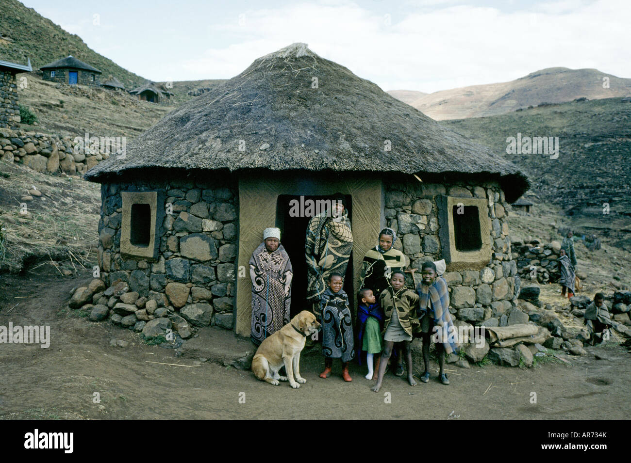 A family of Basotho people in their round stone hut or rondaval in a ...