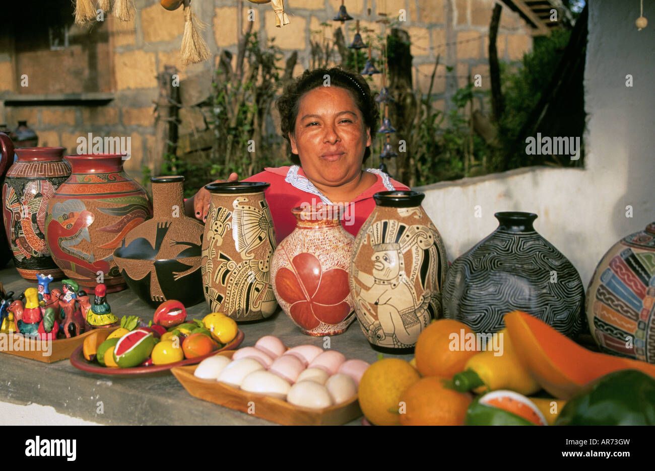 A woman sells decorative vases and cooking pots in her small shop in a ...