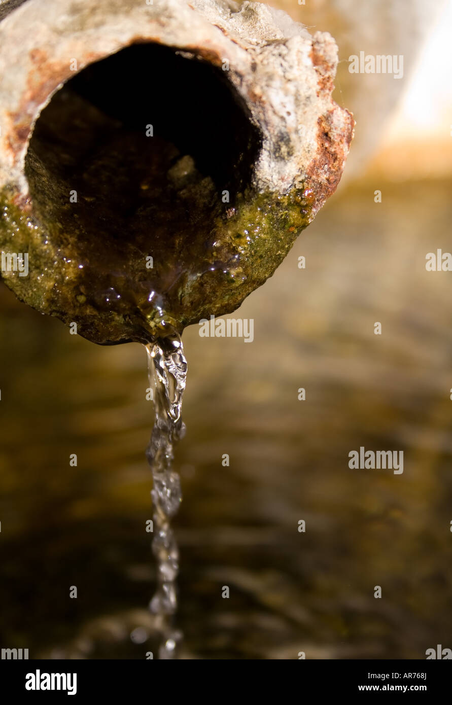 Thin string of water pouring from an old fountain pipe Stock Photo - Alamy