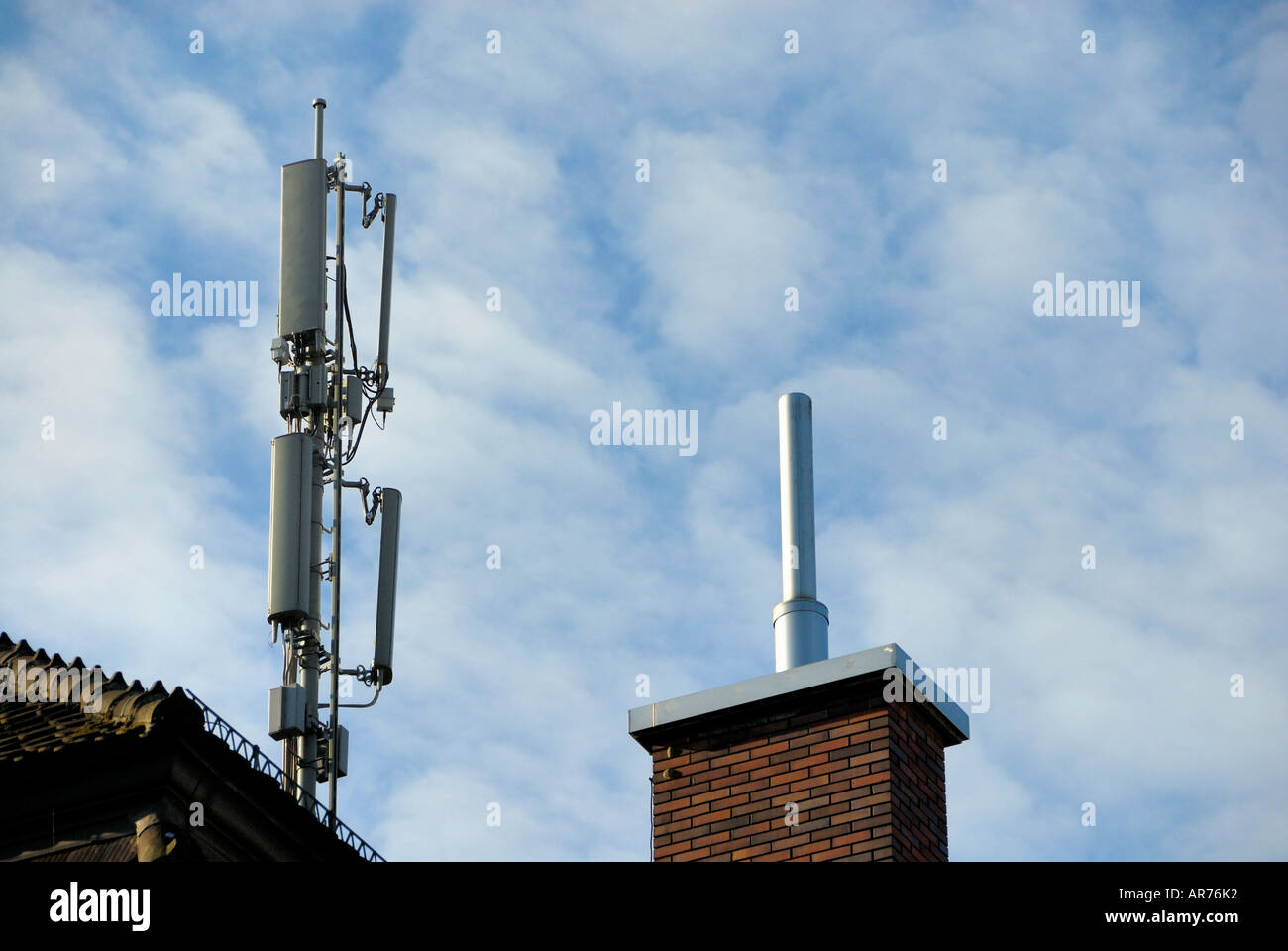 antenna for cellular phone transmission and chimney on a house roof. (c ...