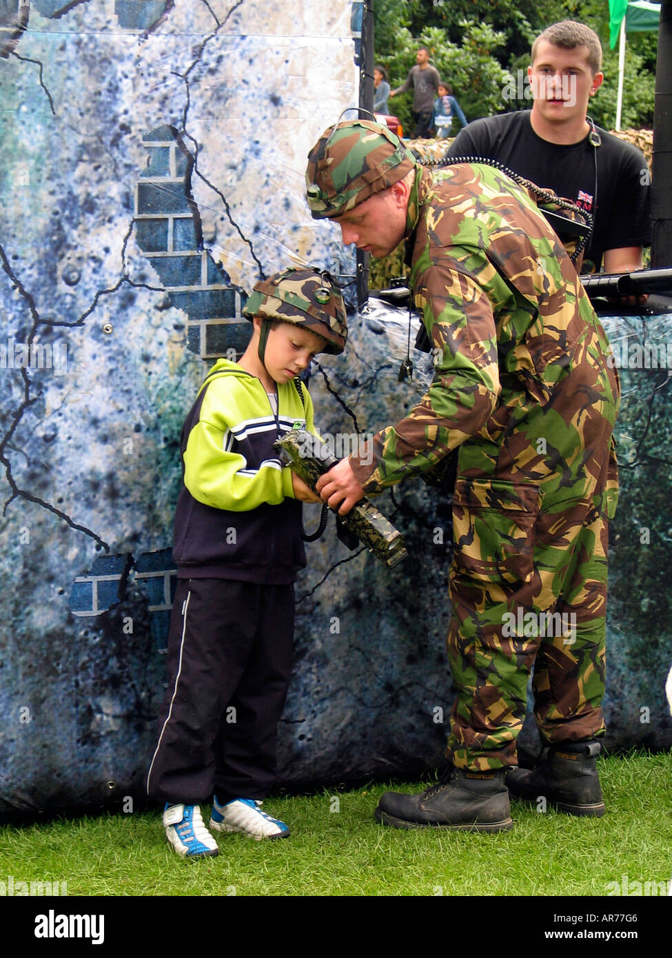 Soldier showing a young boy how to use a gun for War Games in a Stock ...