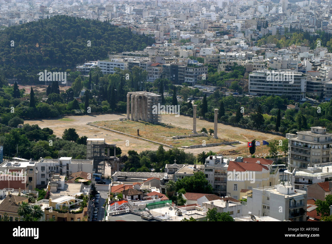 Ancient stone columns and ruins surrounded by the modern city of Athens ...