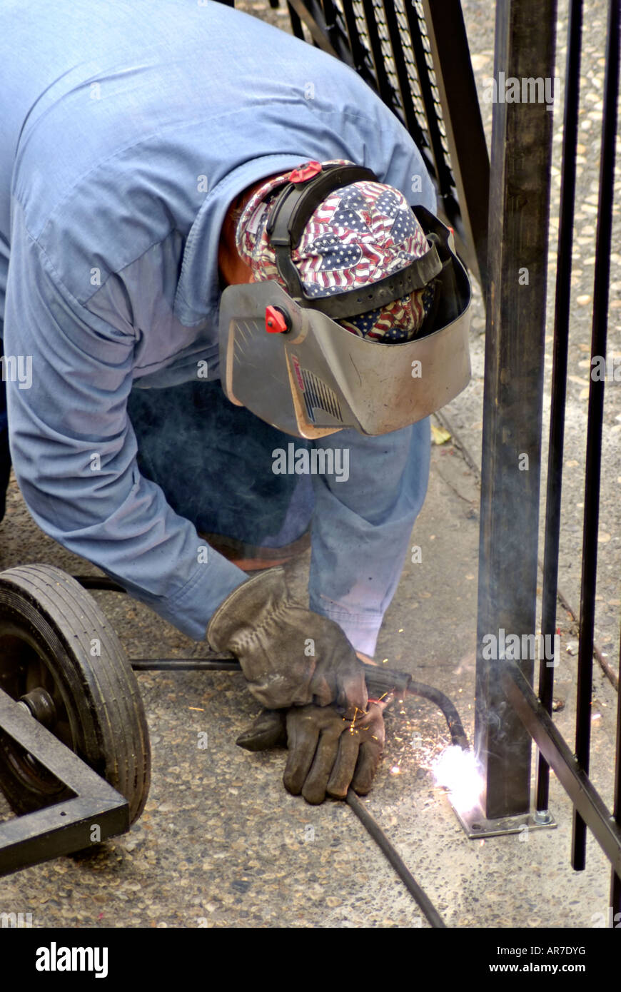 Fence installation worker welds a seal on a new fence post Stock Photo ...