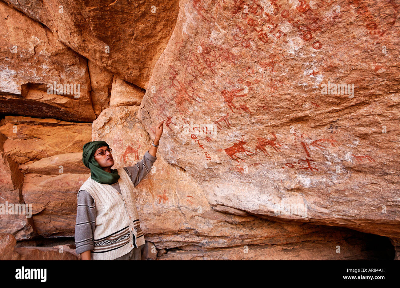 Tourist guide explaining rock art in the Akakus Mountains Sahara Desert ...