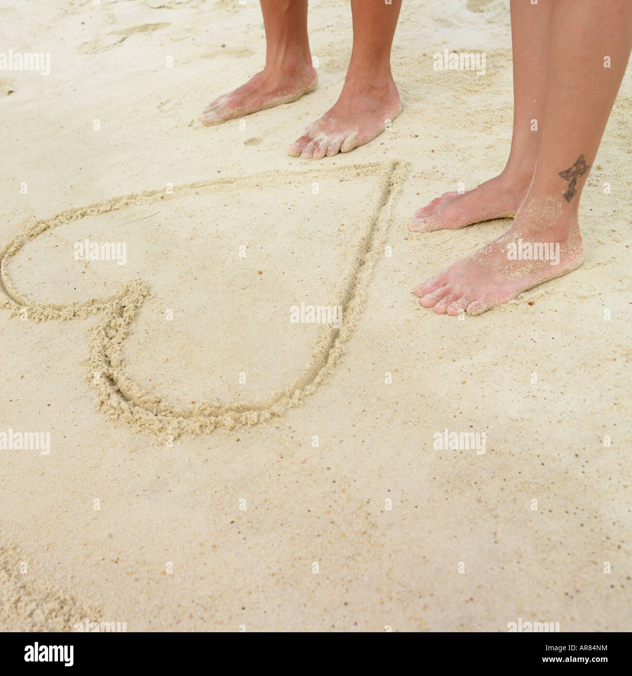 Close-up of a couple's feet and a heart shape drawn on sand Stock Photo ...